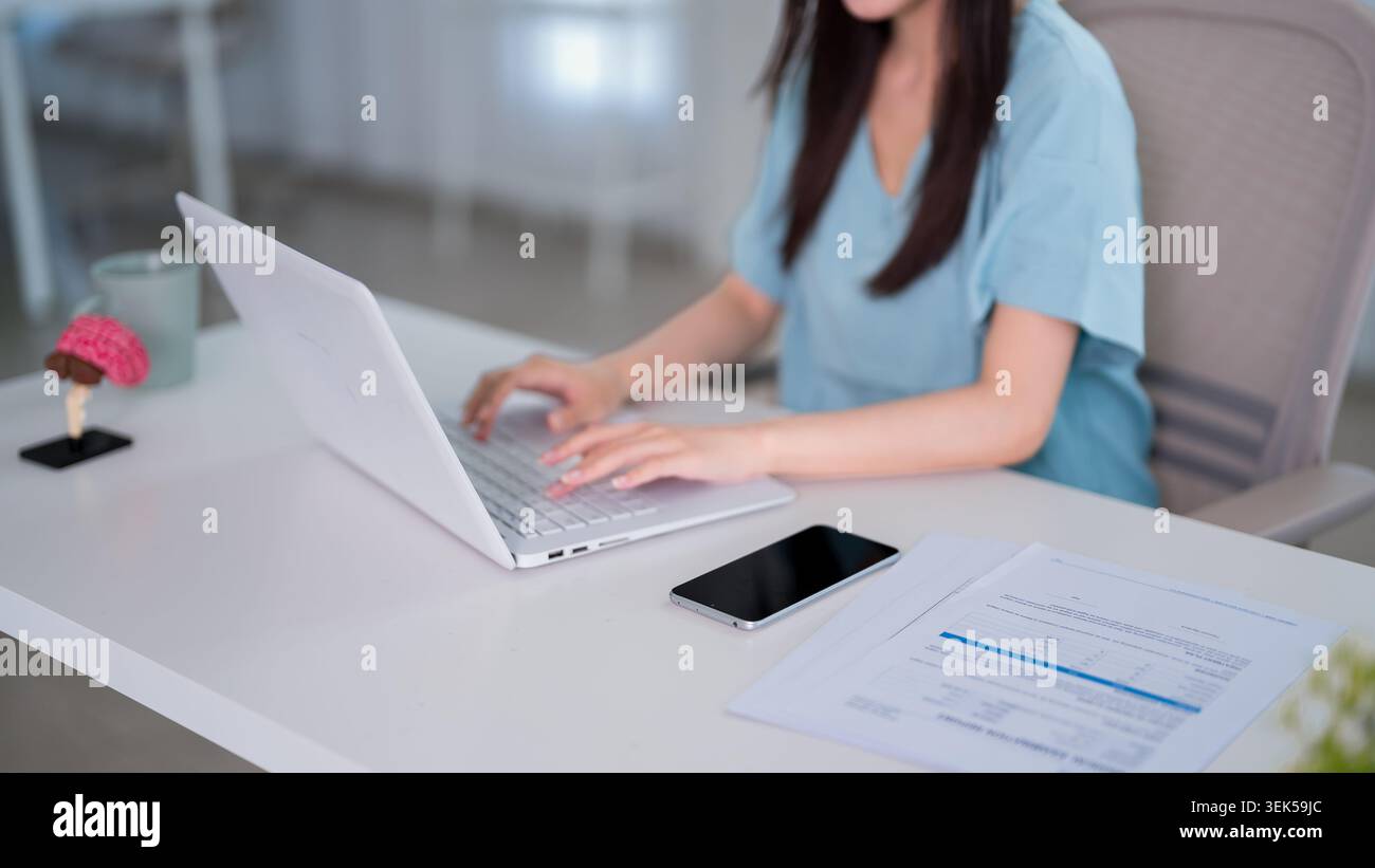 Asian female doctor using laptop computer working on medical documents ...
