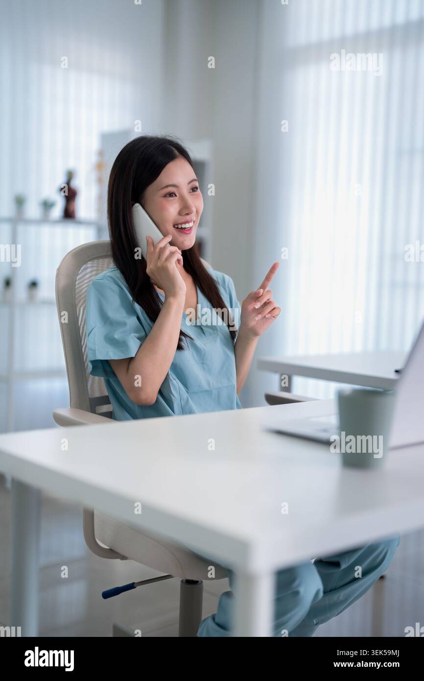 Asian healthcare worker talking on phone in bright modern office ...