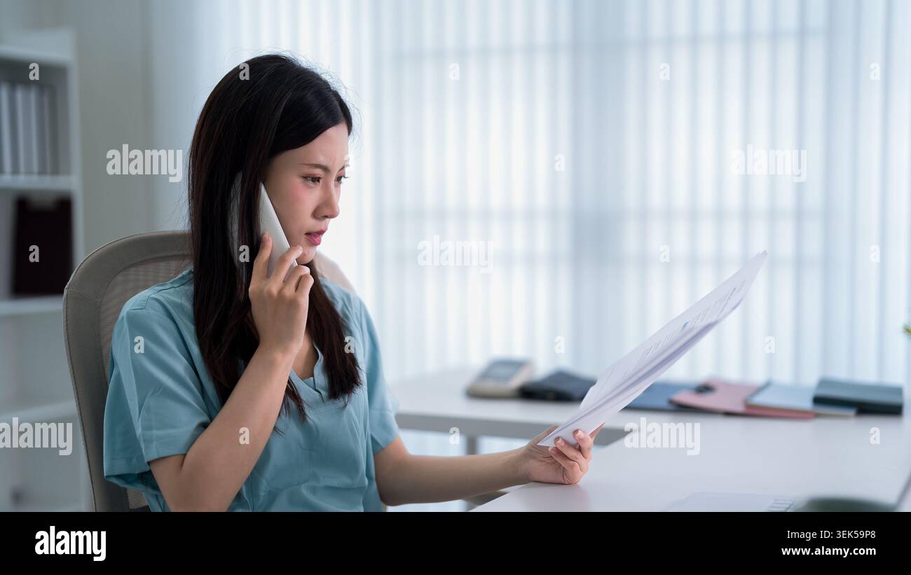 Asian woman professional talking on phone while reading document at ...