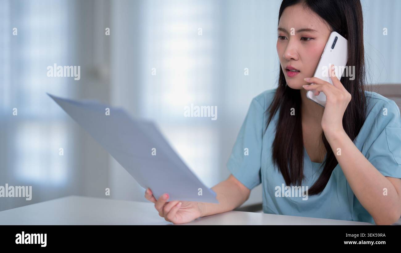 Asian woman medical professional talking phone while reading document ...