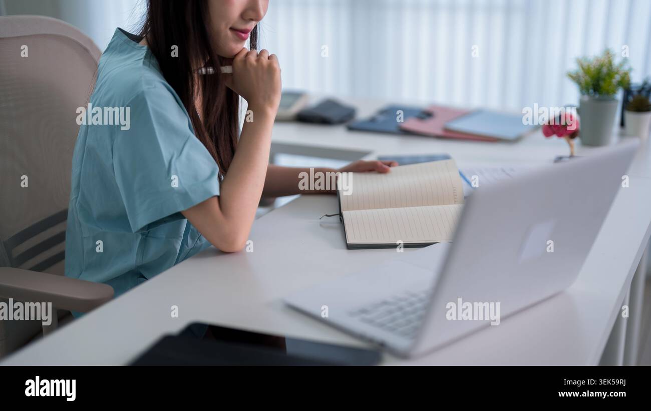 Asian women doctor working from home using laptop computer writing ...