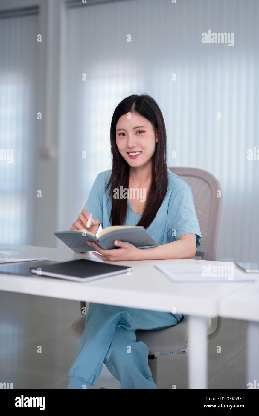 Asian women doctor writing notes in medical office with bright modern ...
