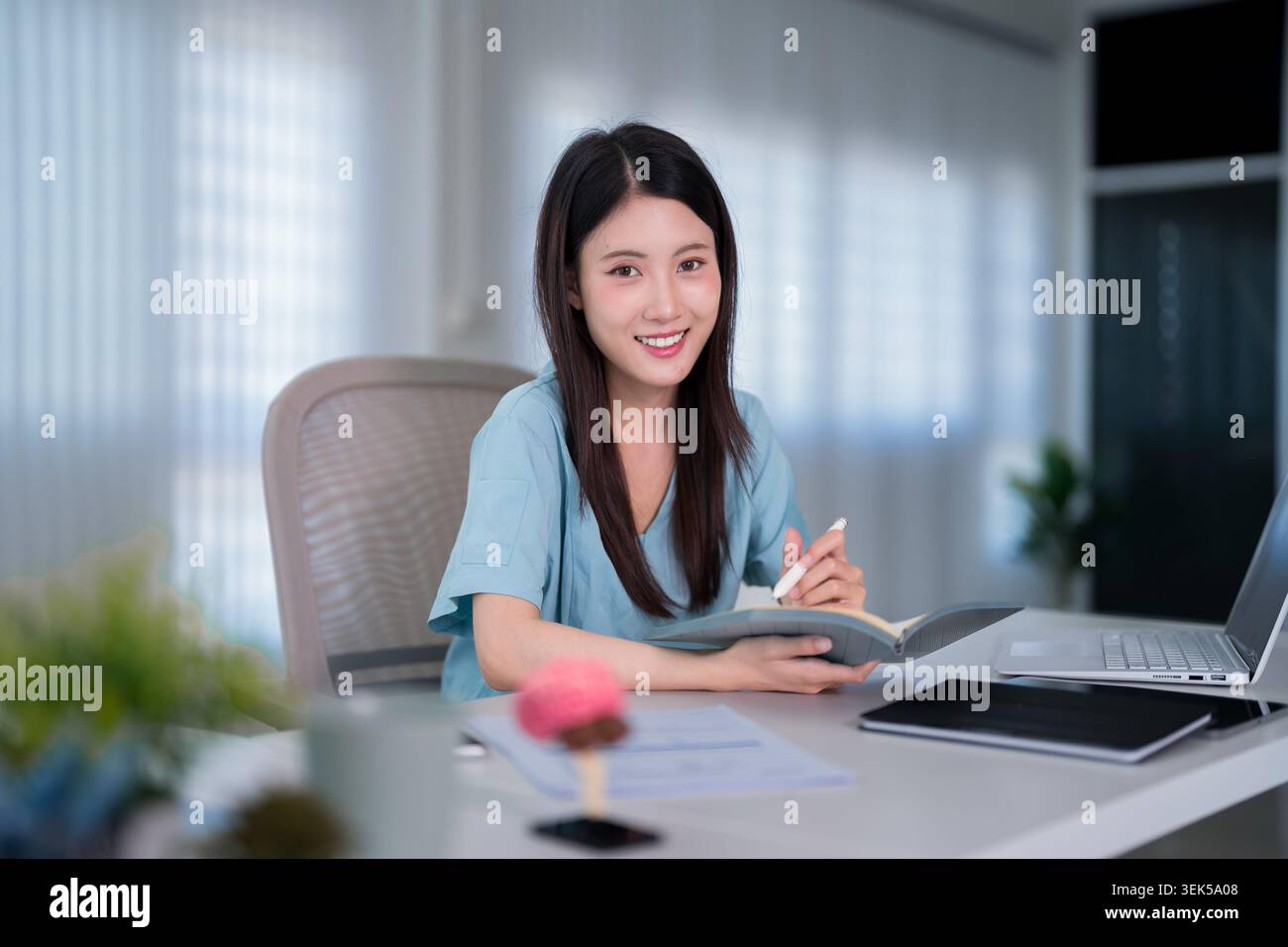 young Asian woman professional writing notes in book at modern office ...