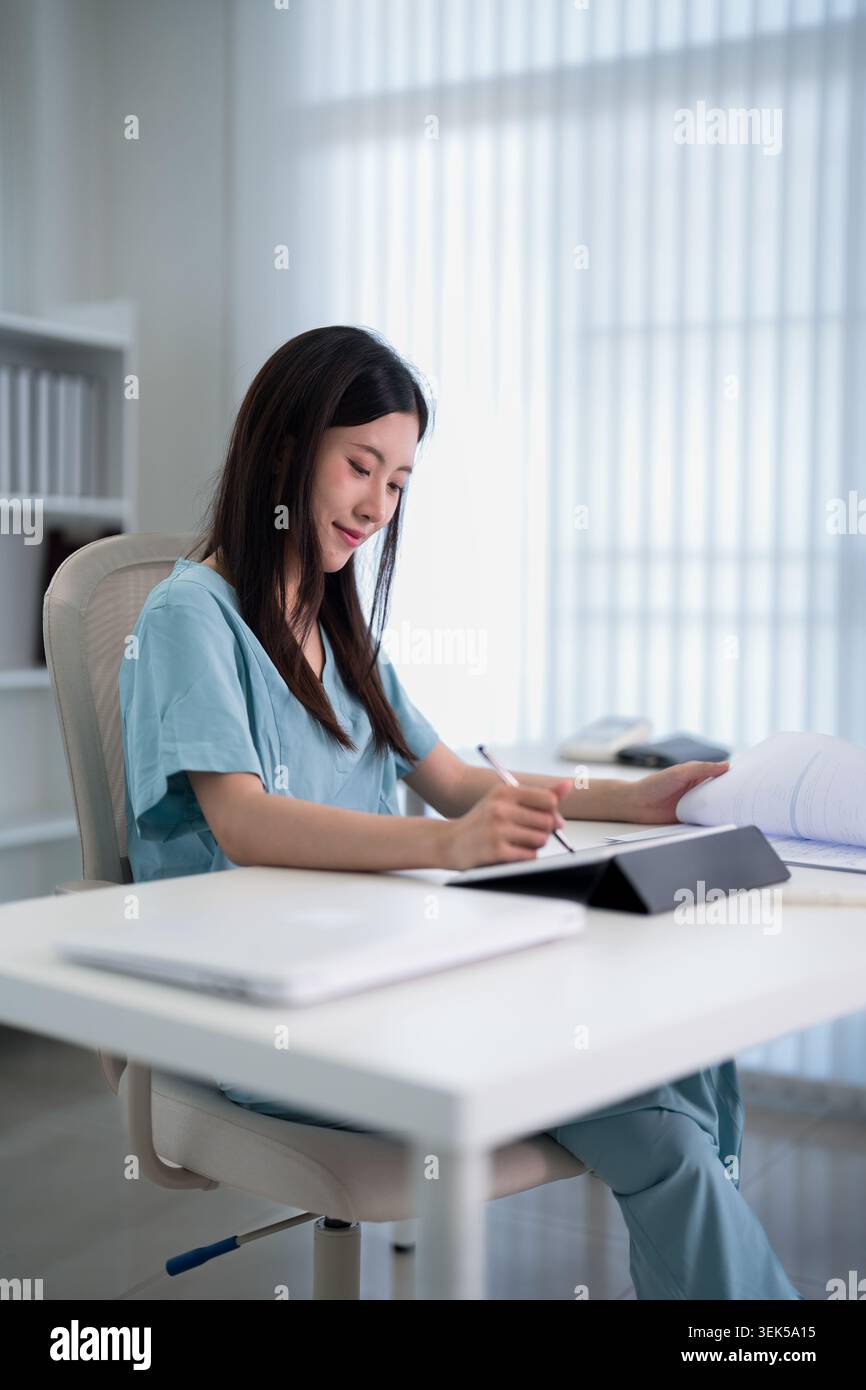 Asian healthcare worker writing medical notes documentation at desk in ...