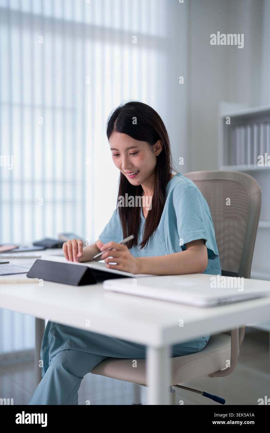 Young Asian female doctor using tablet device reviewing medical ...