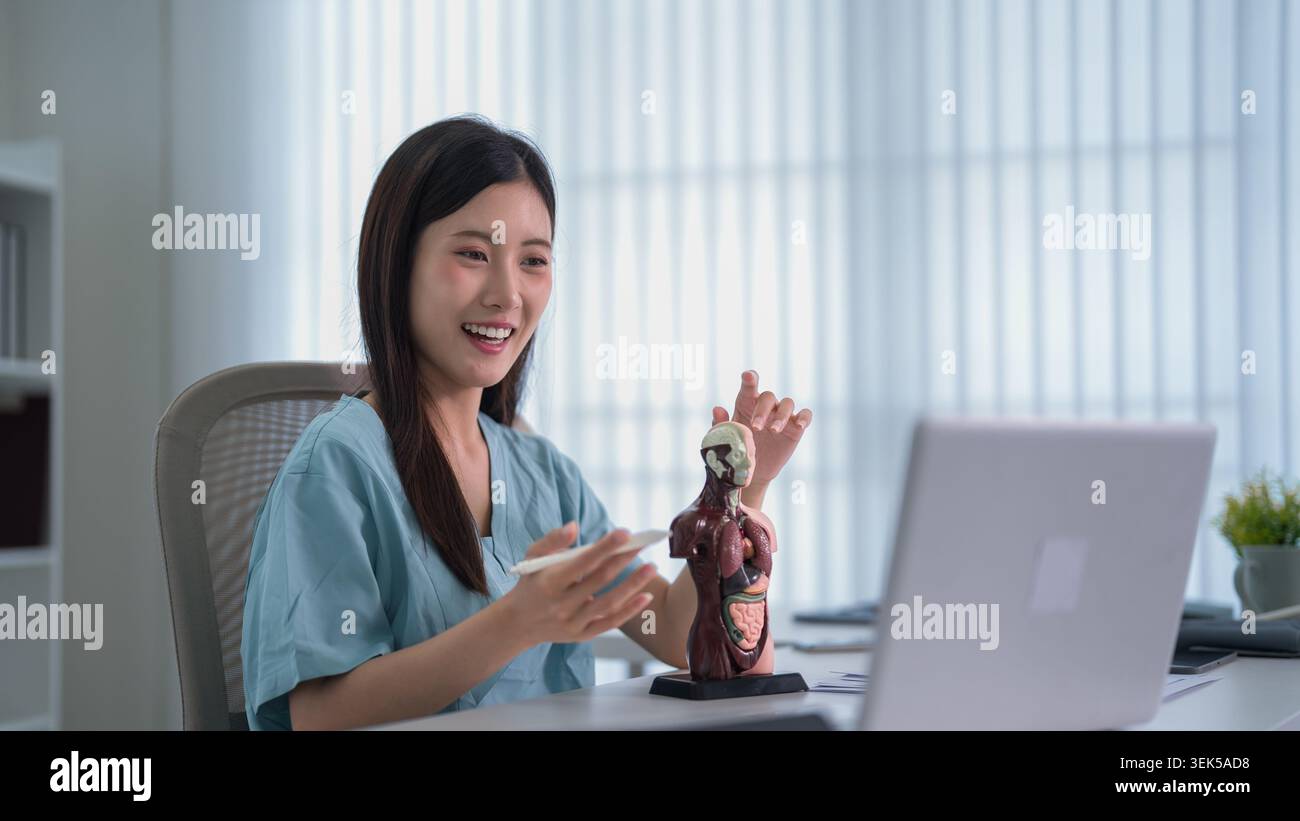 Asian female doctor presenting anatomical heart model during online ...