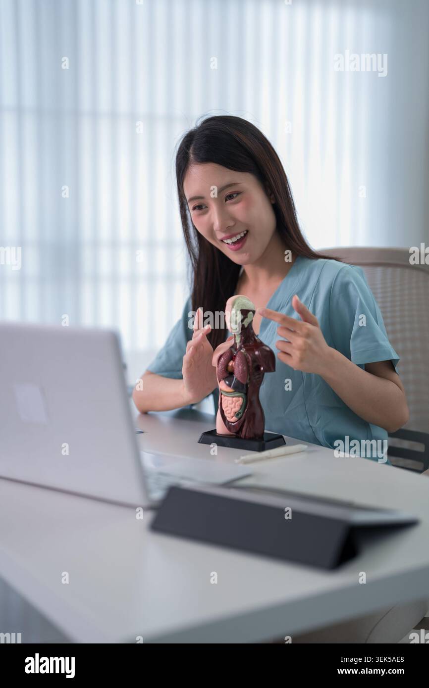 young Asian female doctor presenting anatomical model during video ...