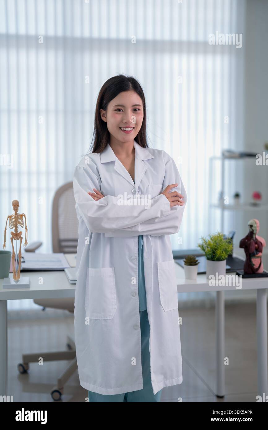 young Asian woman doctor standing with arms crossed in white lab coat ...