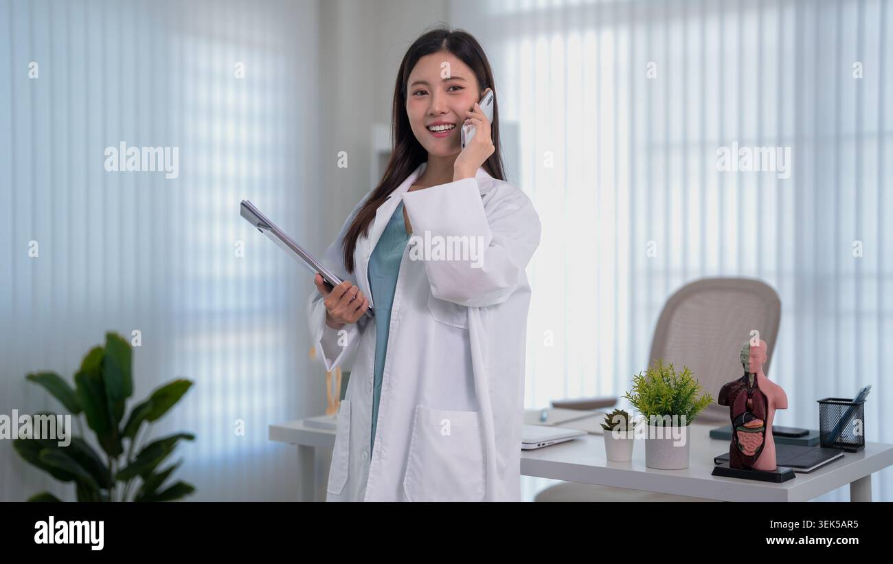 Young Asian professional female doctor communicating via mobile phone ...