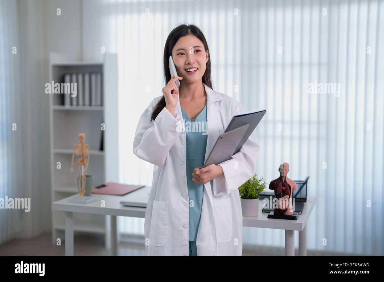 Young Asian woman doctor in white lab coat holding clipboard with pen ...