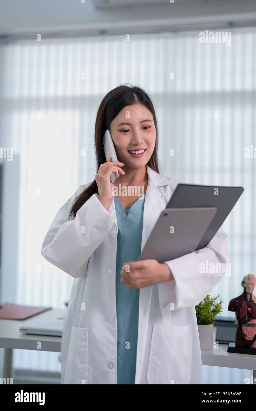 Asian female doctor talking phone holding tablet telehealth ...