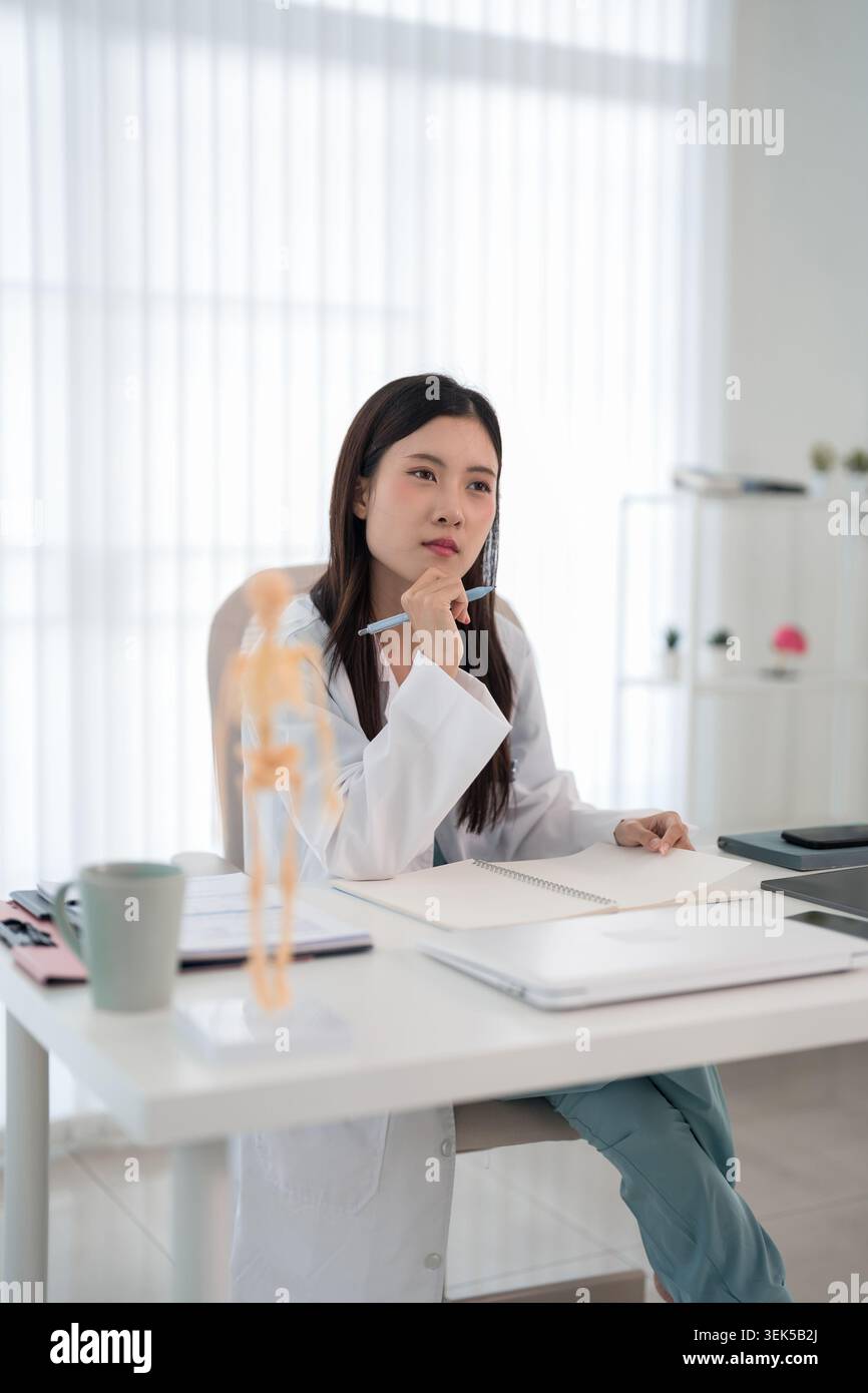 Young Asian woman professional thinking contemplating while writing ...