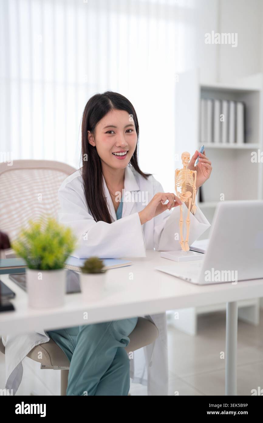 Young Asian doctor holding human skeleton model presenting medical ...