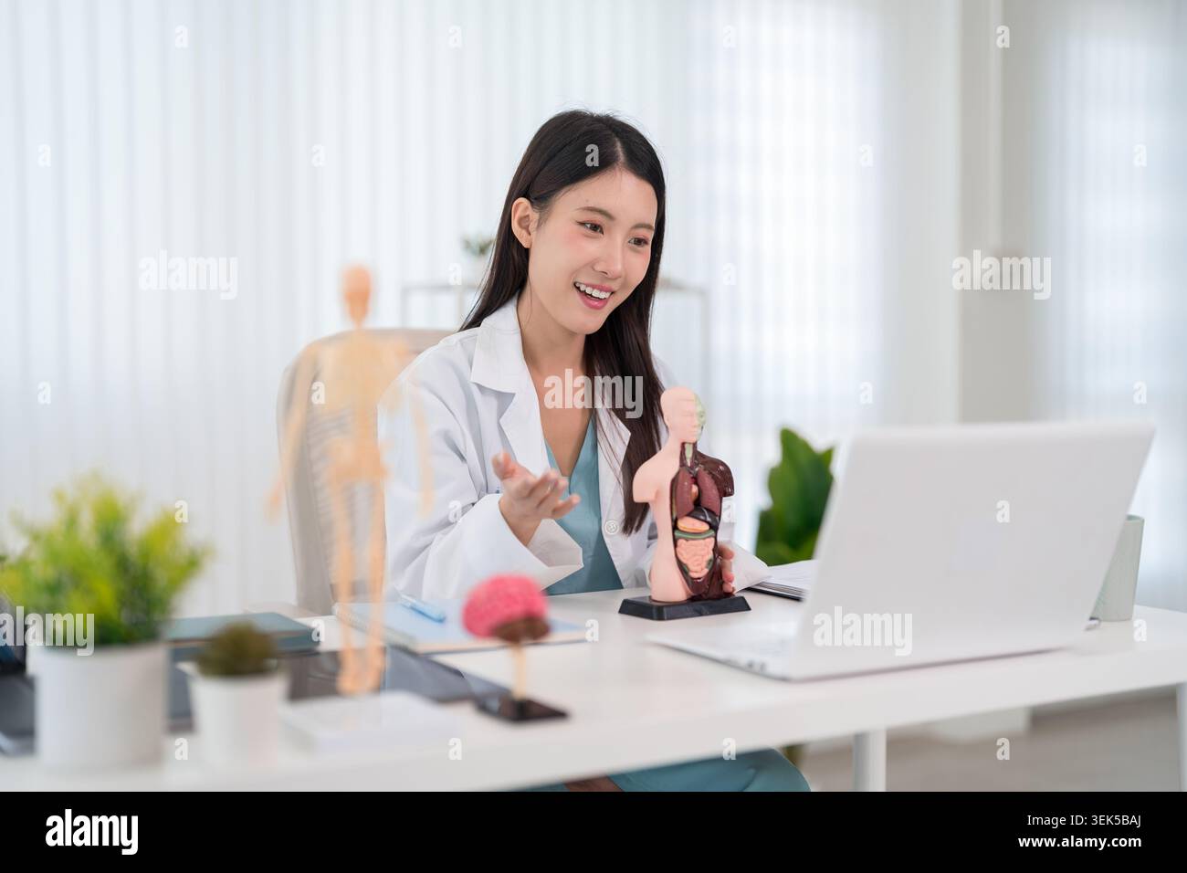 Young Asian female physician presenting anatomy model during online ...