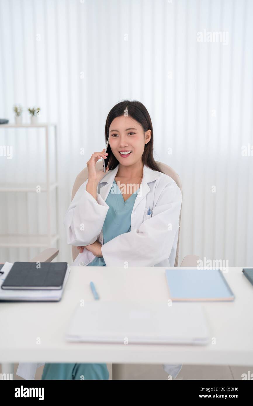 young Asian woman doctor talking phone medical consultation patient ...