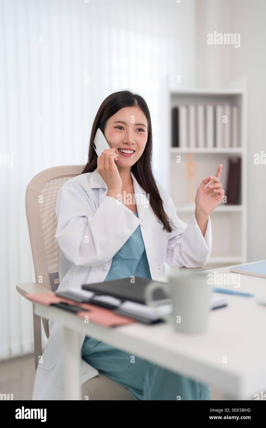 young Asian woman doctor talking smartphone pointing gesture while ...