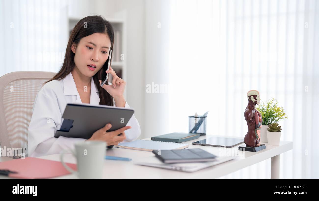 Young Asian female doctor using digital tablet talking on phone for ...