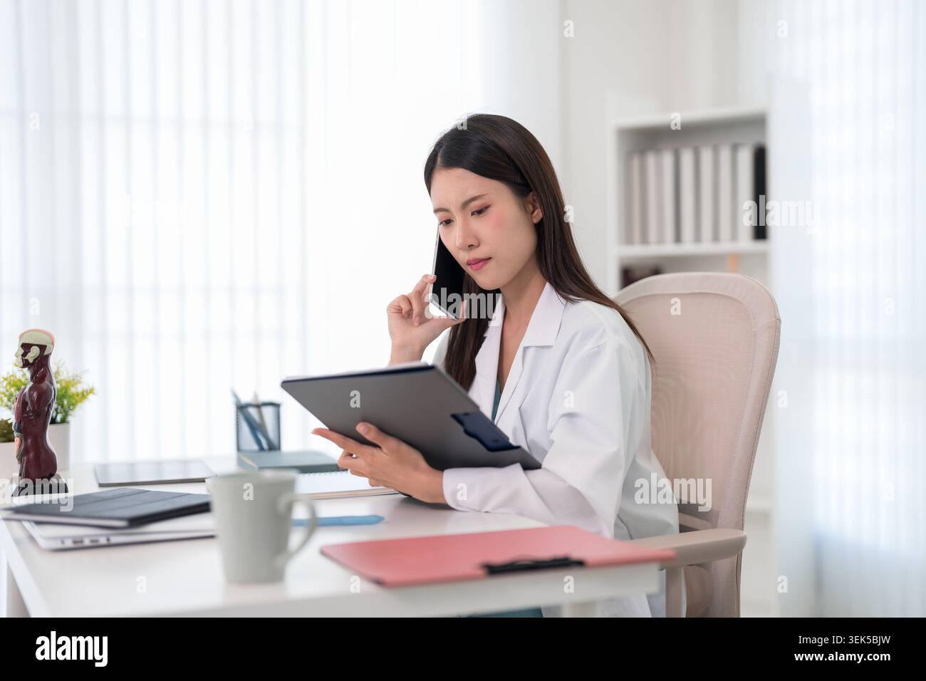 Asian female doctor using phone and tablet for medical consultation in ...