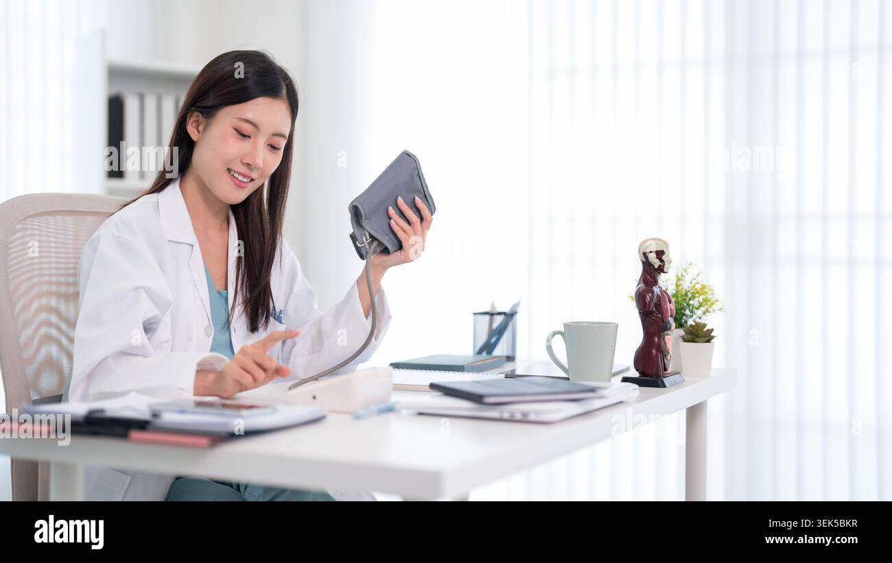 Asian female doctor using tablet writing notes medical records ...