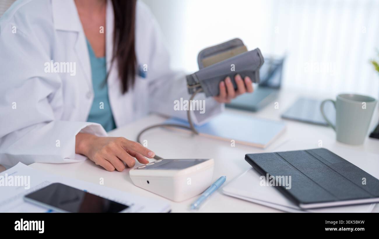 Asian female doctor measuring blood pressure with sphygmomanometer at ...