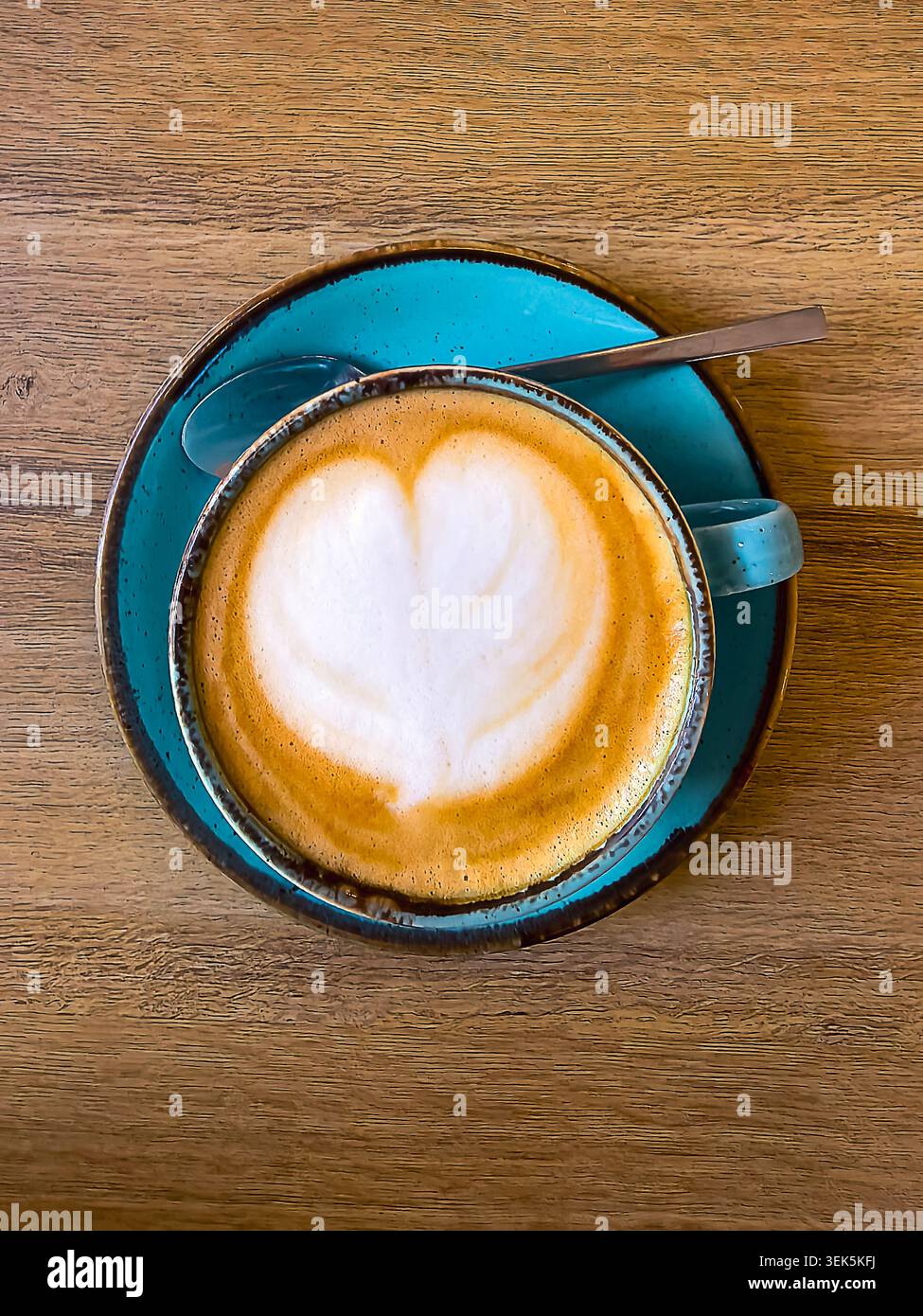 Close-up of creamy heart-shaped latte art in a turquoise cup on a ...