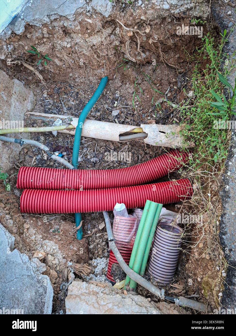 A construction trench lies open in the ground displaying a mix of ...