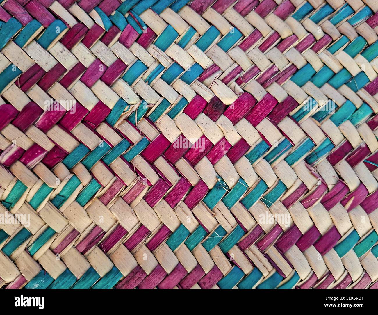 Craftspeople create a colorful mat using palm fronds, showing a ...