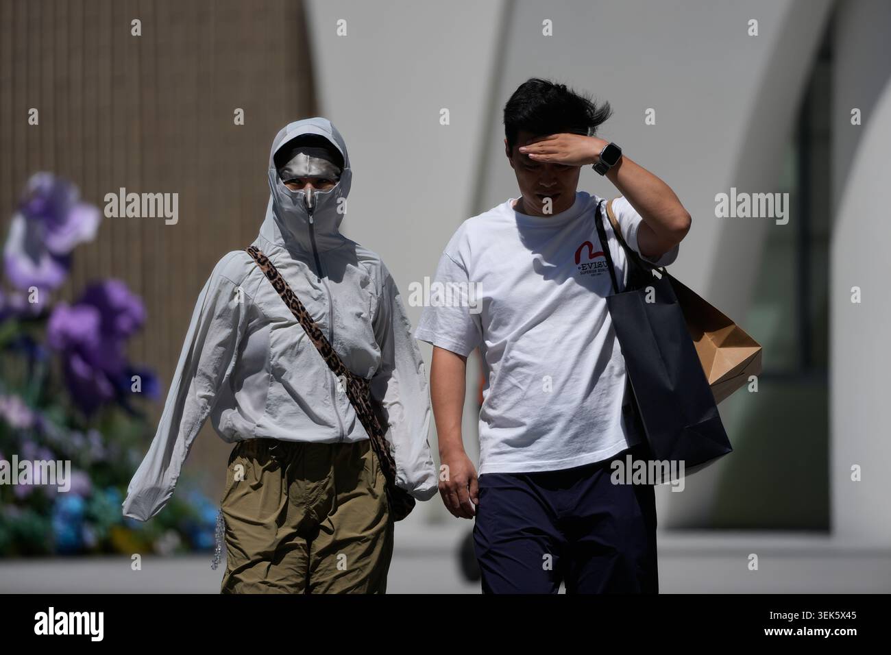 A woman wearing a sun protection clothing walks at an outdoor shopping ...
