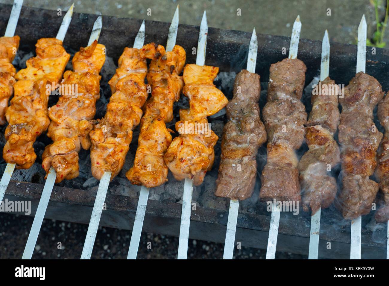 Close-up of marinated meat skewers grilling over hot charcoal, with ...