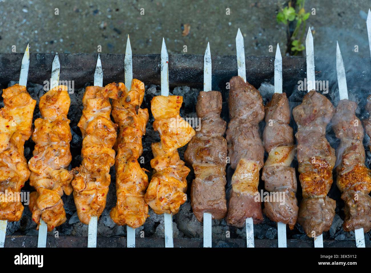 Close-up of marinated meat skewers grilling over hot charcoal, with ...