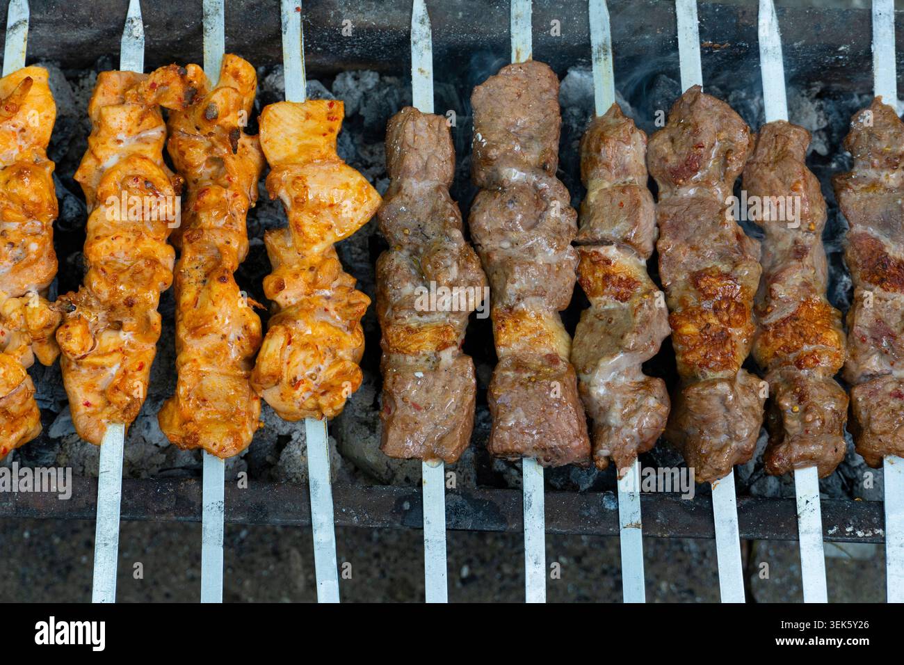 Close-up of marinated meat skewers grilling over hot charcoal, with ...