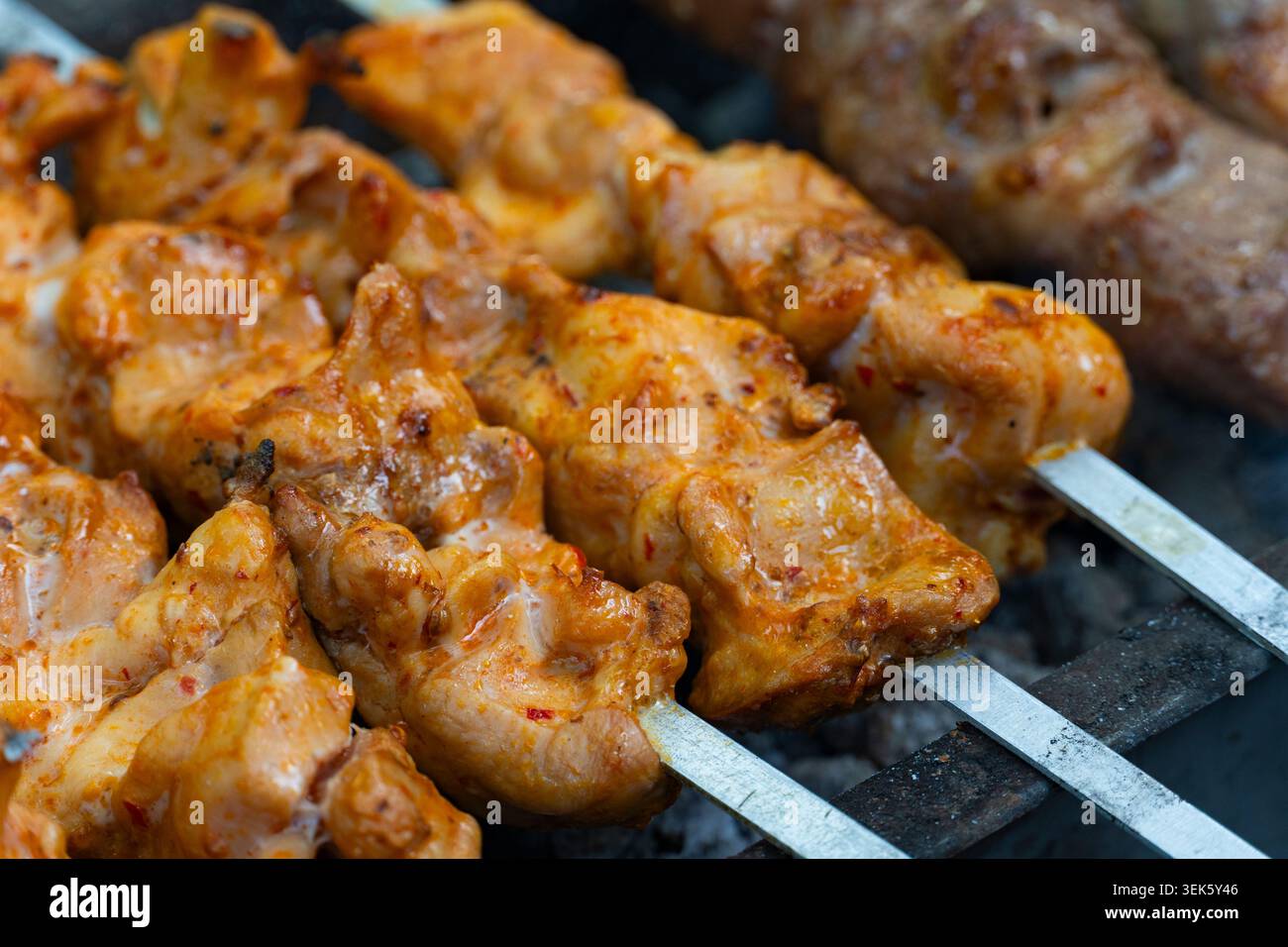 Close-up of marinated meat skewers grilling over hot charcoal, with ...