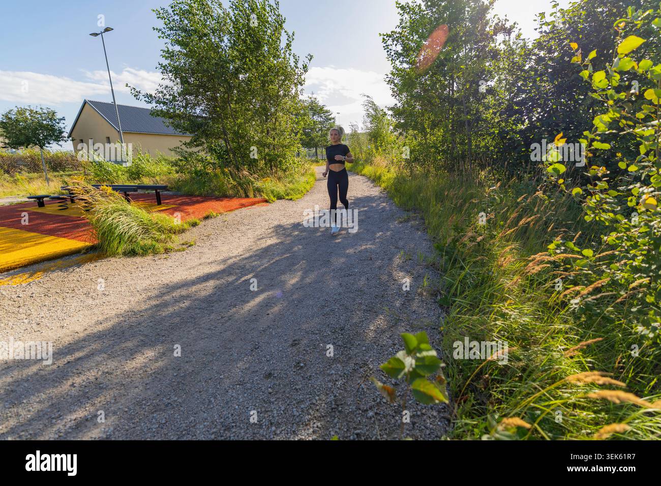 A woman practices jogging on a gravel path in a lush outdoor ...