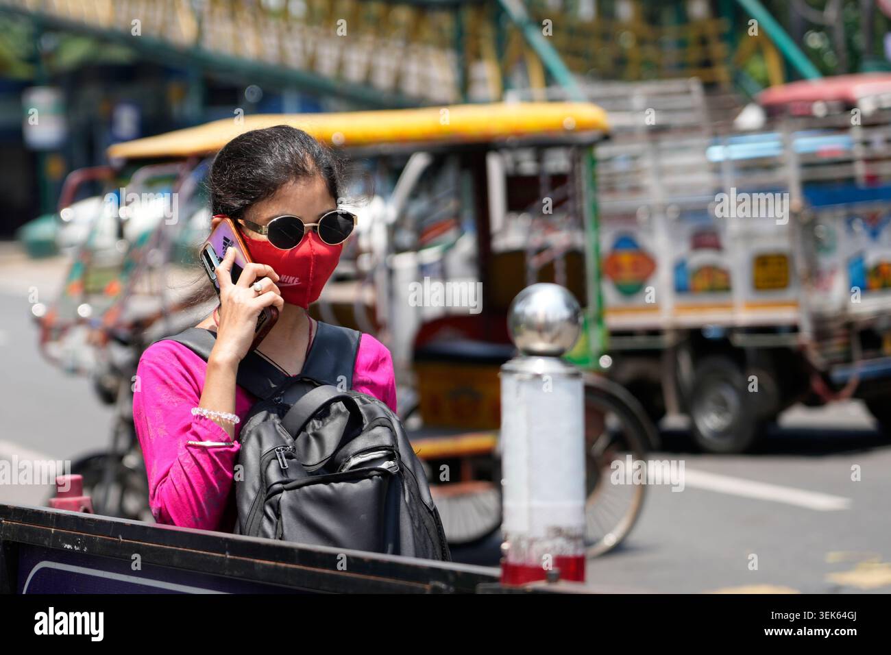 A woman covering her face walks in the sun on a hot summer day in ...