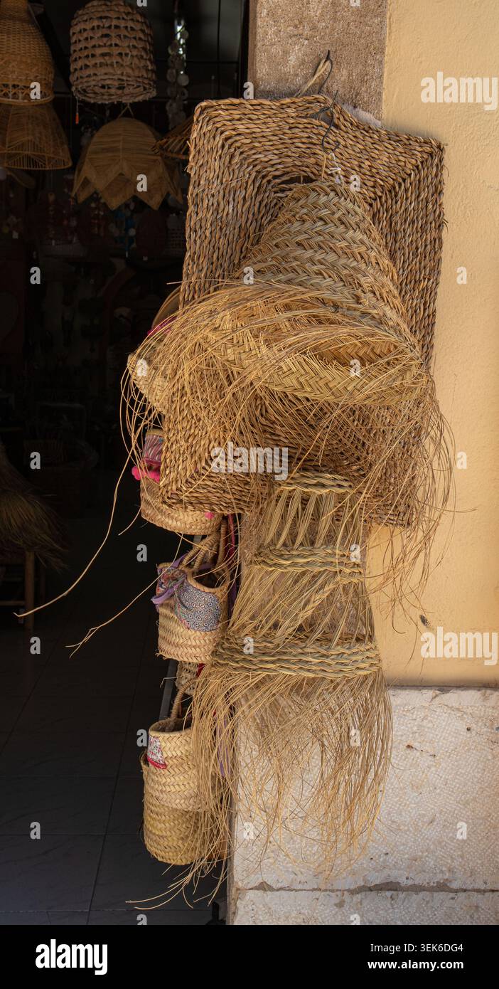 Traditional wicker hats, bags, and baskets hang outside a rustic ...