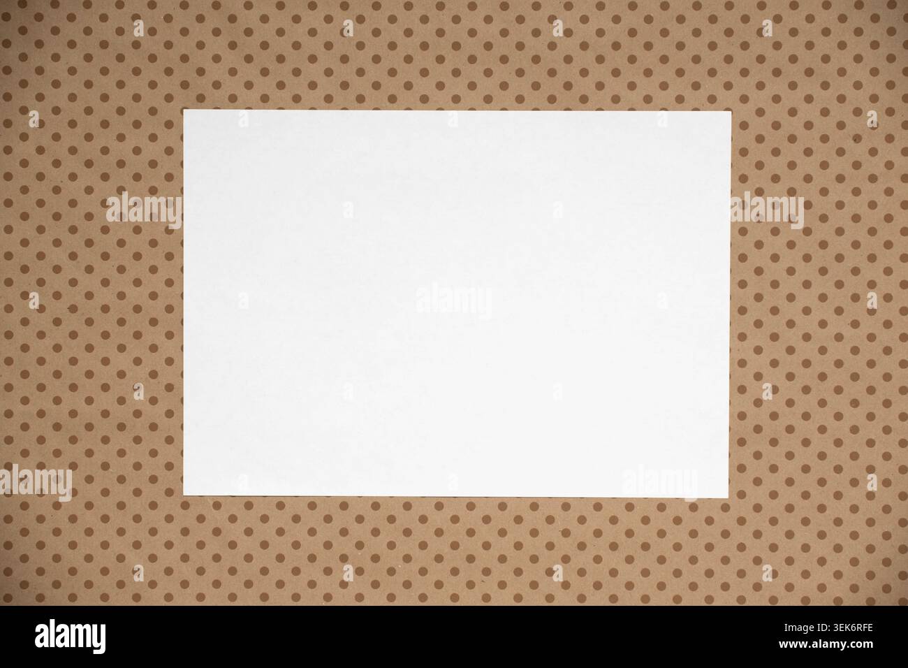A blank piece of white paper sits on a brown background with dots. It ...