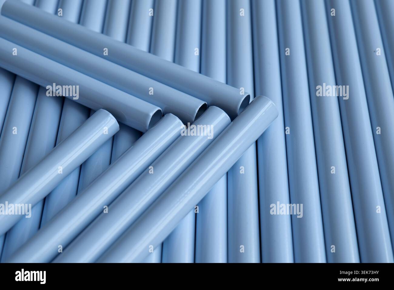 Hand holding white plastic pipes against a background of more pipes ...