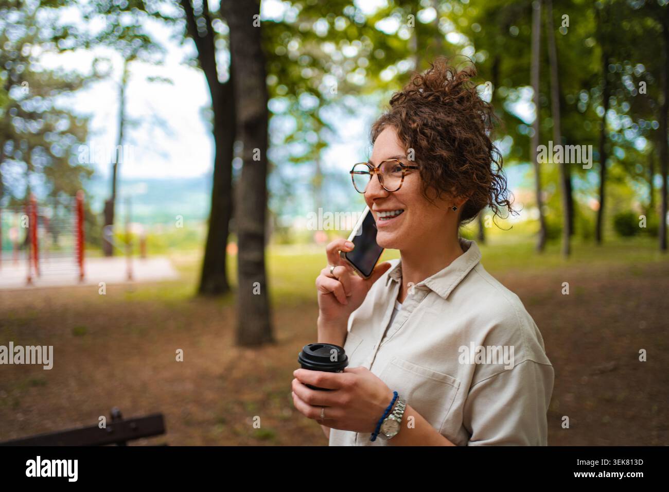 Woman enjoying a phone call and coffee outside, laughing and ...