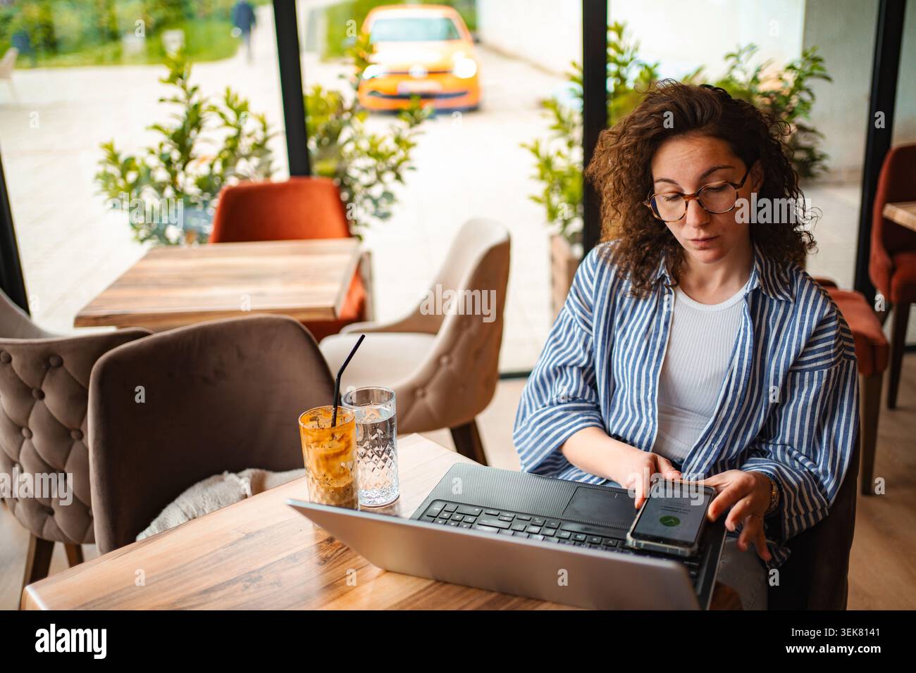 Woman concentrating on her phone while telecommuting from a local ...