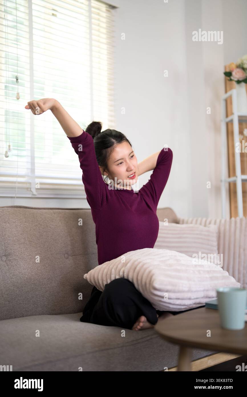 young Asian women stretch arm relax morning waking up sitting on living ...
