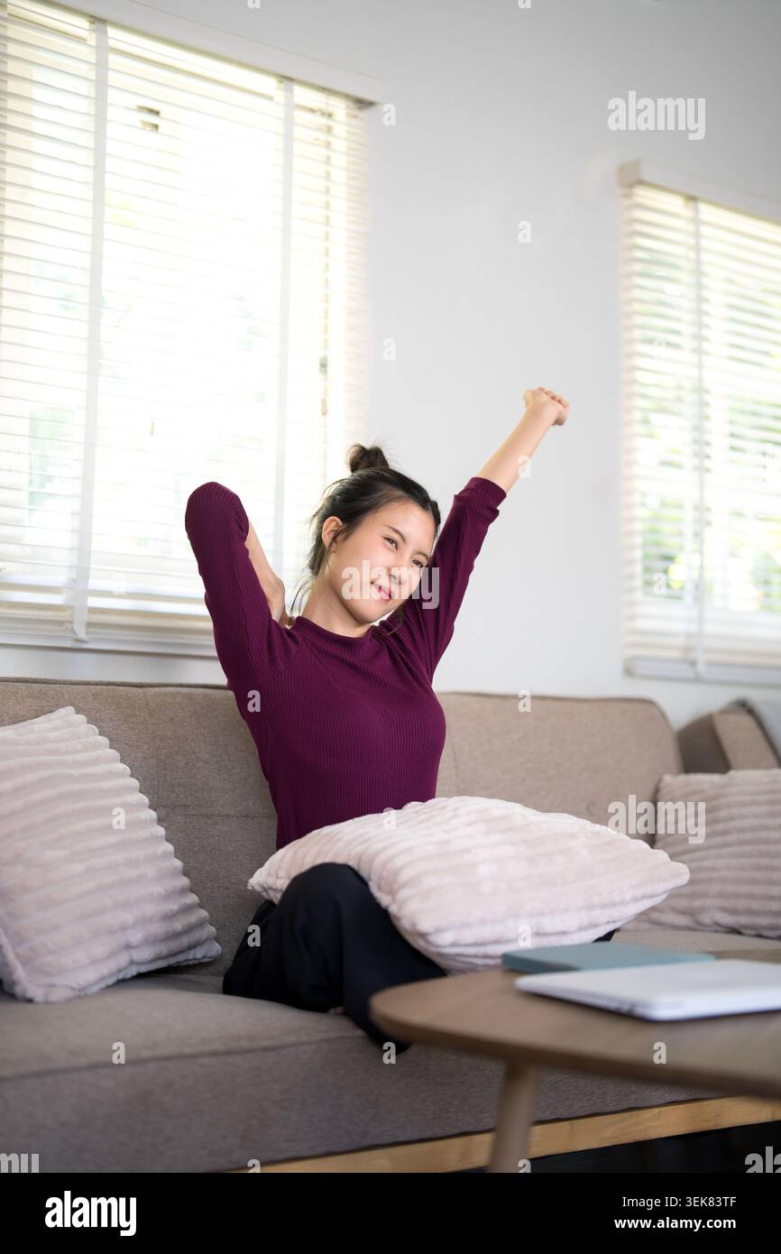 young Asian woman stretching arms after waking up feeling refreshed ...