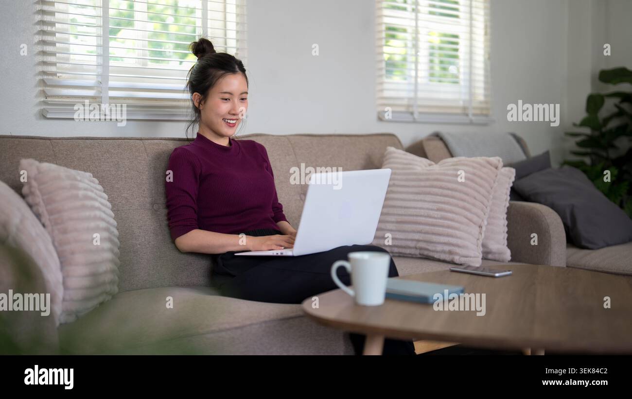 Young Asian woman working from home on laptop computer sitting ...