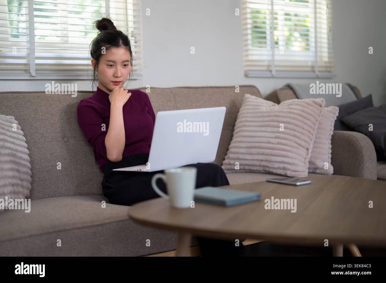 young Asian woman using laptop computer working from home sitting on ...