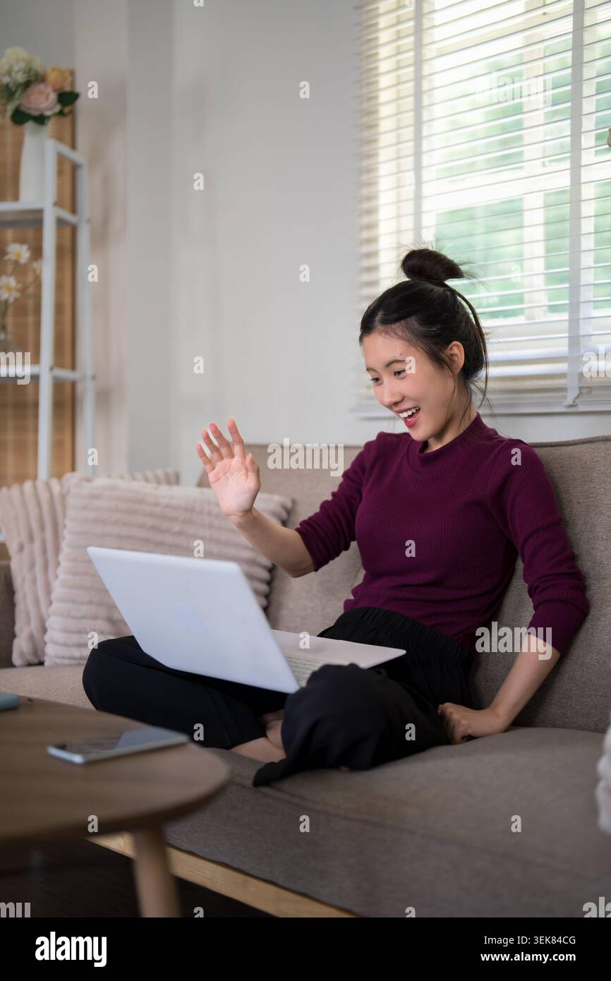 Asian woman healthcare professional doing telehealth video call waving ...