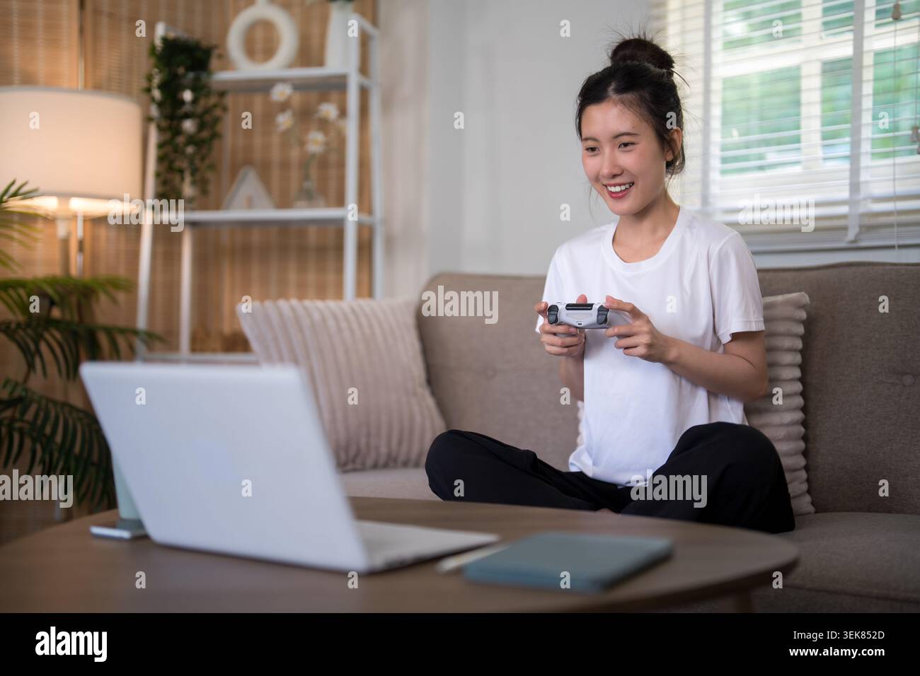Asian young women sitting on couch holding gaming controller playing ...