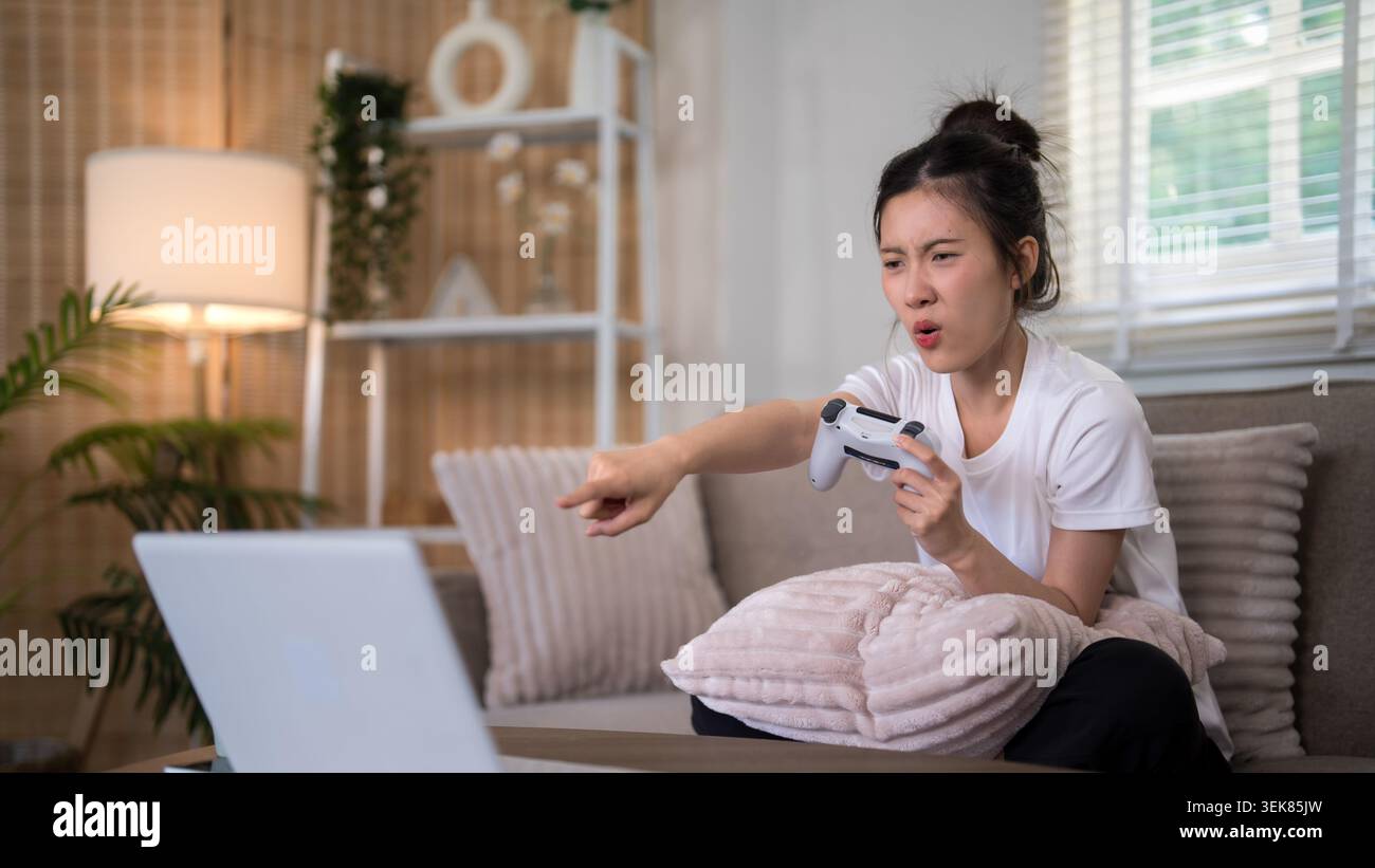Young Asian female gamer playing video game with controller relaxing on ...