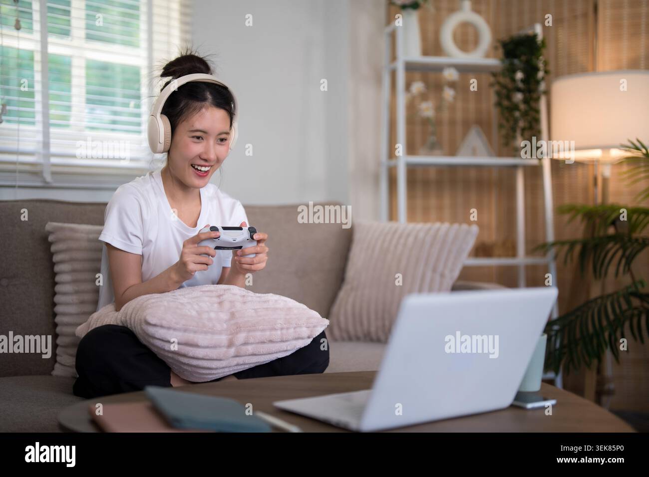 happy young Asian woman wearing headphones playing video games using ...
