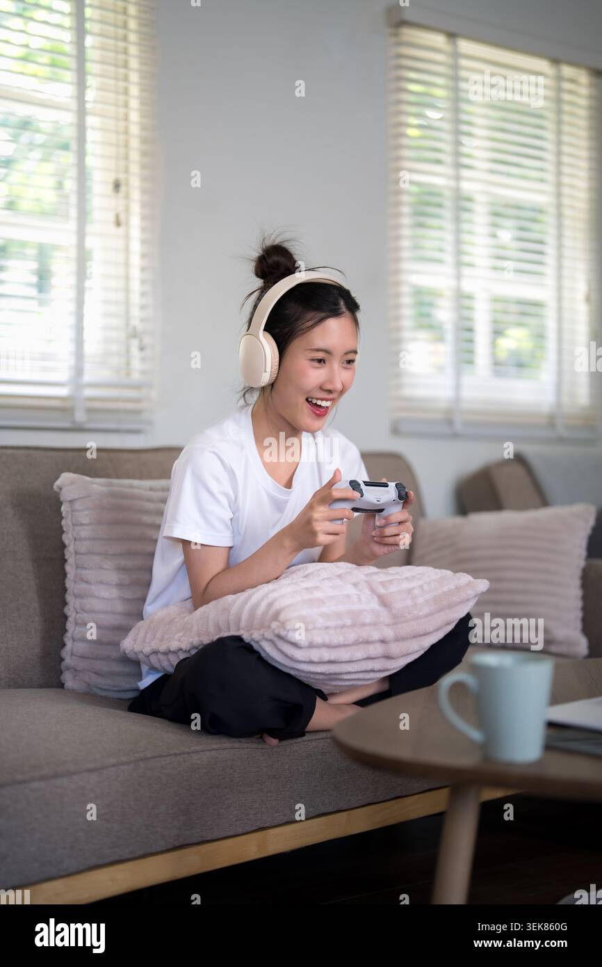Asian young women sitting relaxed on sofa with headphones holding ...