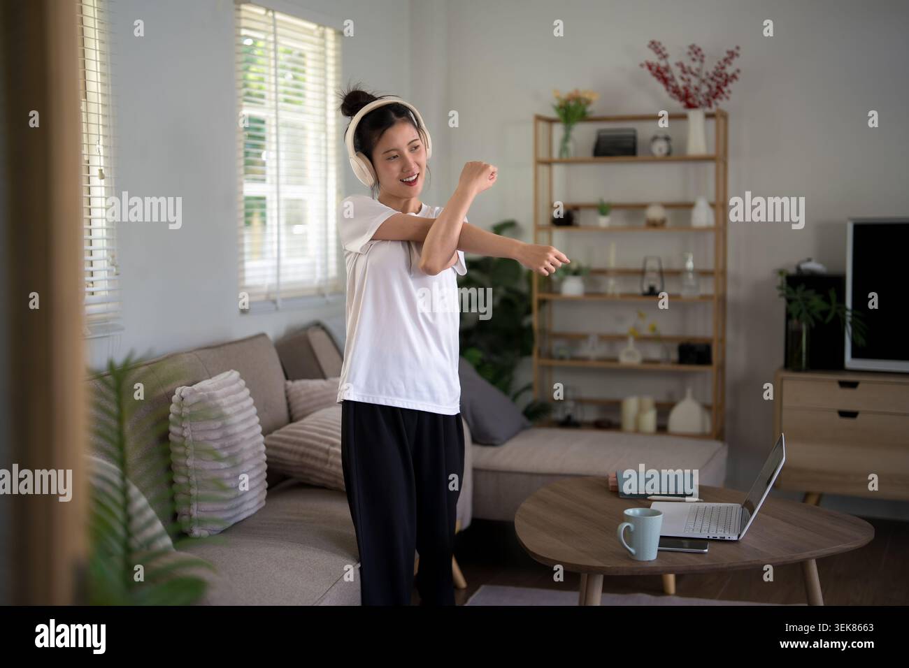 Asian woman stretching arms wearing headphones doing morning exercise ...