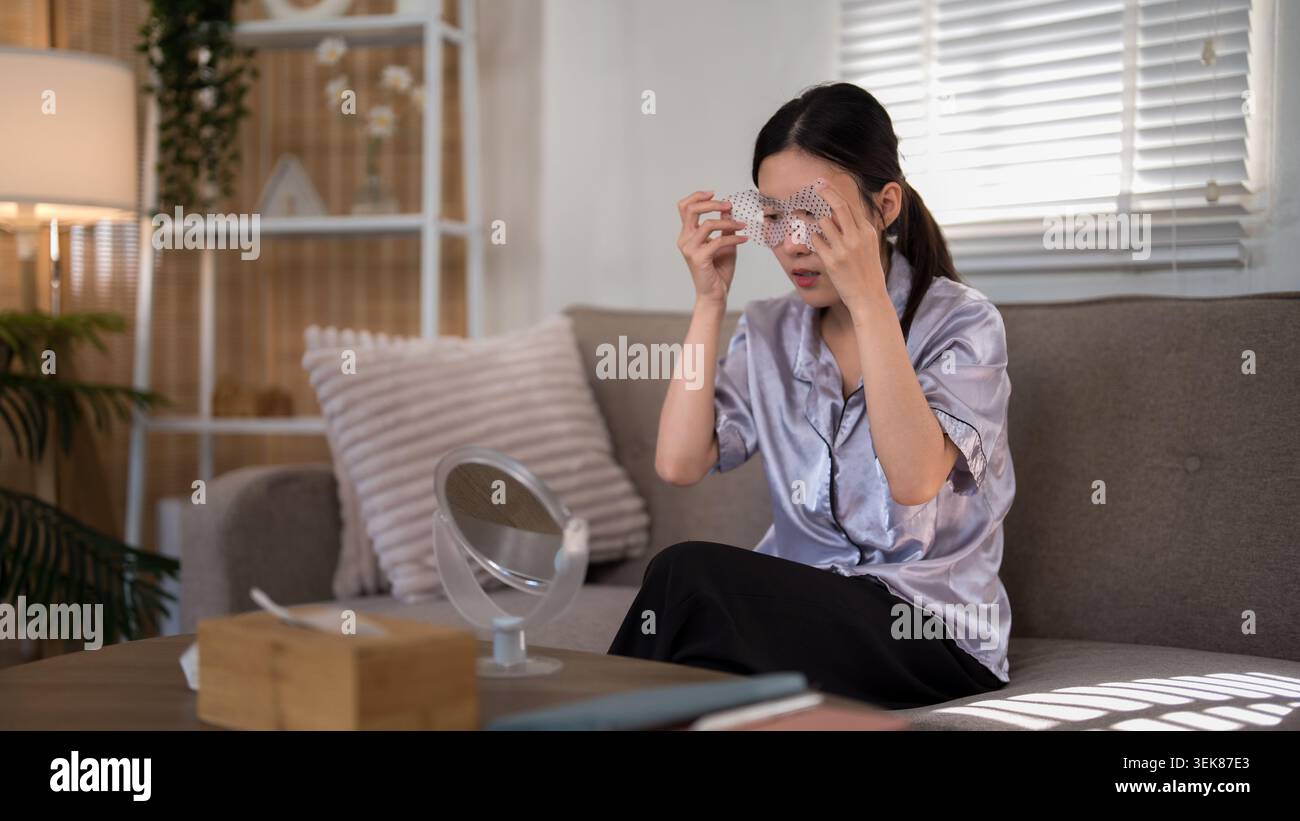 Young Asian woman using eye gel mask for skincare routine sitting on ...